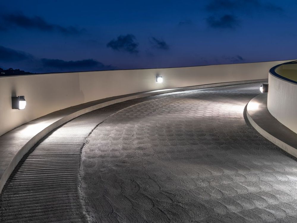Nighttime Walkway with Curving Road and Wall-Mounted Light Fixtures ...