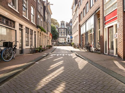 Amsterdam city street with bicycles parked next to tall buildings ...