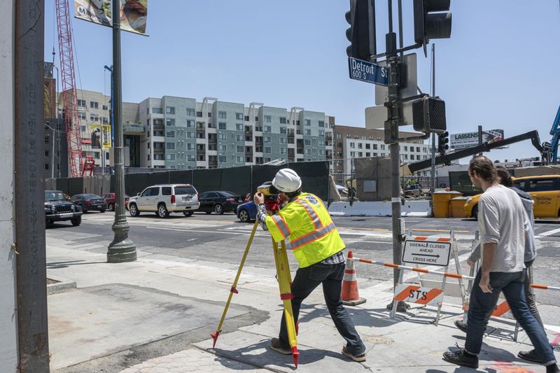 Construction worker measuring traffic lanes on a street in Los Angeles ...