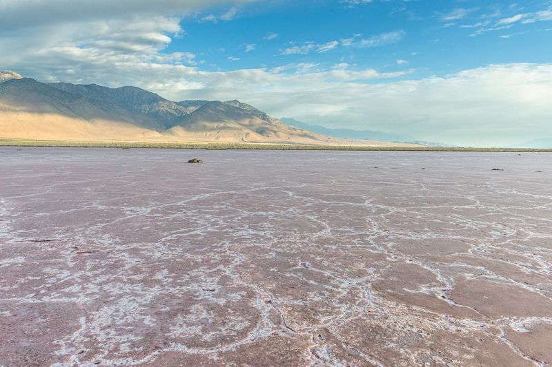 Wide desert plain covered in salt and sky with large mountains in ...